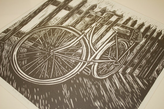 Linocut print of a bike against a fence
