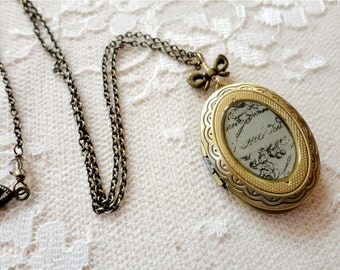 Oval locket necklace with blue - grey cursive script and bow, Lovely As ...