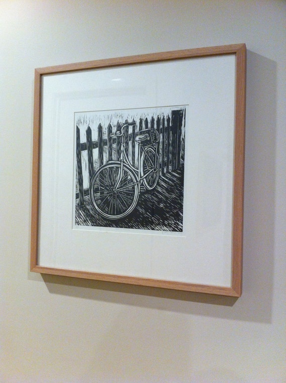 Linocut print of a bike against a fence